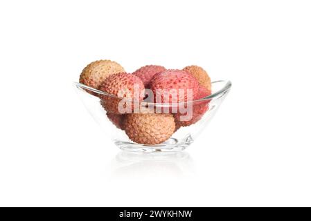 Fresh lychee fruits in white ribbed bowl with green leaves on textured ...