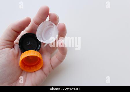Woman's hand holding plastic lids on white background, space for copy ...