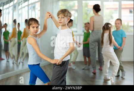 Preteen children learn to dance tango under guidance of a teacher in ...