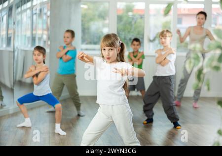 Positive juvenile girl engaged in Breakdancing in training room with ...