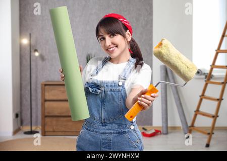 Young woman with roller, ladder, houseplant and paint cans on yellow ...