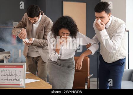 Business people covering faces with wet tissues in burning office ...