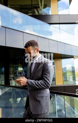 Suited man with arms crossed stands proudly before a sleek building ...