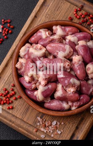 Raw chicken hearts with salt, spices and herbs on a dark concrete ...