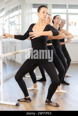 Woman practicing demi plie at barre during group ballet class Stock ...