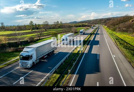 Convoy of white Trucks with containers on highway, cargo transportation ...