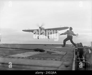 A Fairey Barracuda aircraft lands on HMS Ravager with a batsman giving ...