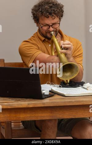 One-armed male trumpeter playing and composing music at his home ...