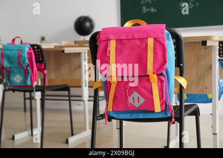 Schoolbag hanging on chair in classroom, closeup Stock Photo - Alamy