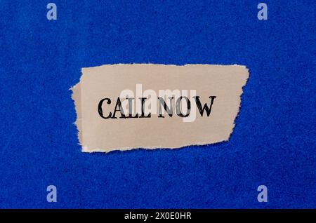 Call now words written on ripped yellow paper with blue background ...