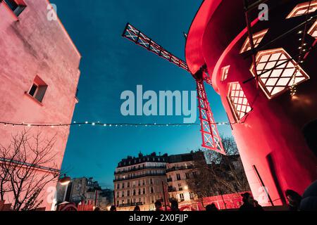 Moulin Rouge at night with lights during French sunset. Spinning moulin ...