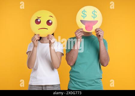 People covering faces with emoticons on light blue background Stock ...
