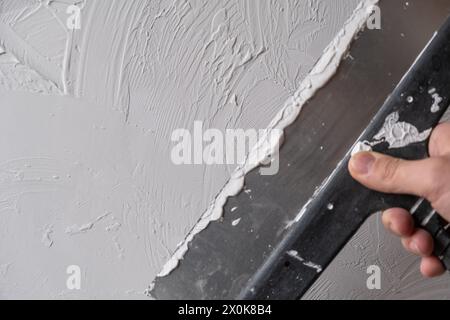 Applying decorative putty. White abstract texture of surface covered ...