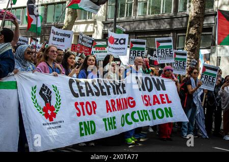 Protestors hold a large banner and placards during the "Say No To ...