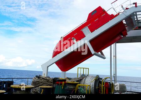 Orange free fall lifeboat secured on white launching ramp and ready to ...