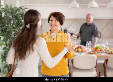 Happy mother meets her daughter, hugs and kisses her. In the background ...