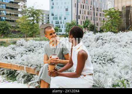 Two diverse women enjoying coffee in a cafe, looking at a digital ...