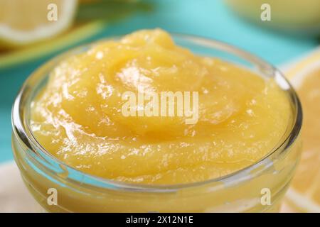 Delicious lemon curd in glass jar, fresh citrus fruit and green leaves ...