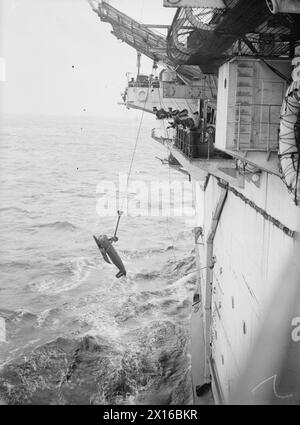 On board HMS Argus in 1940, a signalman uses a cruiser telescope to ...