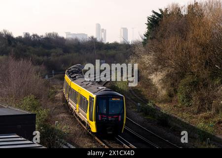 Merseyrail train travelling through wooded landscape with Liverpool ...