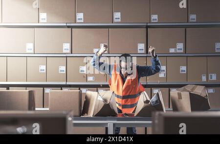Angry rebellious worker punching and smashing boxes on the conveyor ...