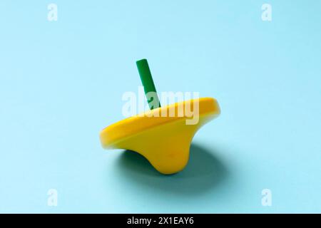 One yellow spinning top on green background, closeup. Space for text ...