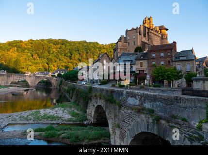 French township of Estaing on bank of Lot River with arched bridge and ...
