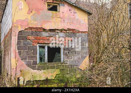 In an aged and crumbling cinder block edifice; a fractured window bears ...