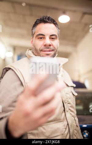 mechanic answers a phone call while checking vehicle levels in a ...