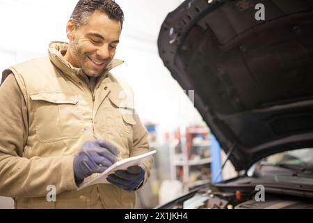 mechanic takes notes while checking levels of vehicle in mechanical ...