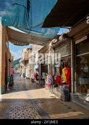 Very narrow cobbled street in the shade that makes a bend at the end in ...