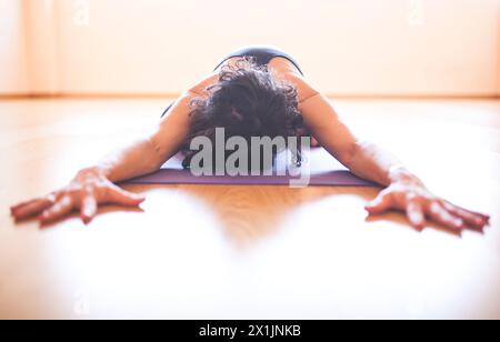 unrecognizable woman yogi lying face down with hands extended forward ...