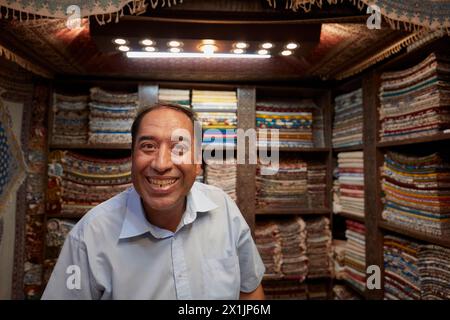 Portrait of a grinning Iranian handicraft seller who looks like once ...