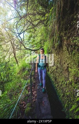 Description: Female toursit hiking along green rainforst hike trail ...
