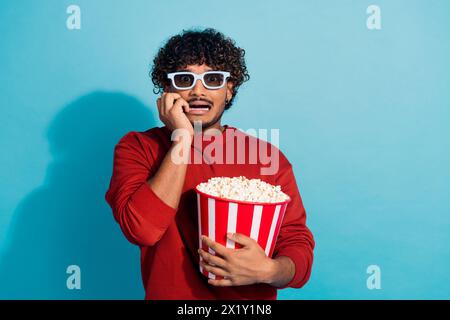 Photo of scared young man watching in stupor crazy horror movie sipping ...