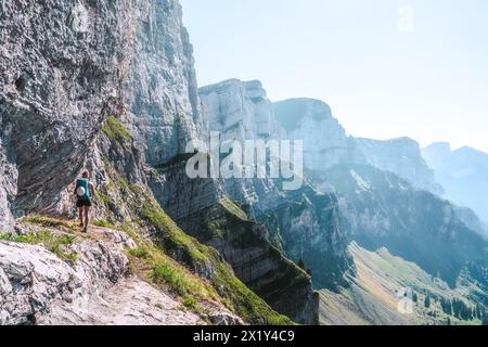 Description: Young woman walks on scenic hiking trail with view on lake ...