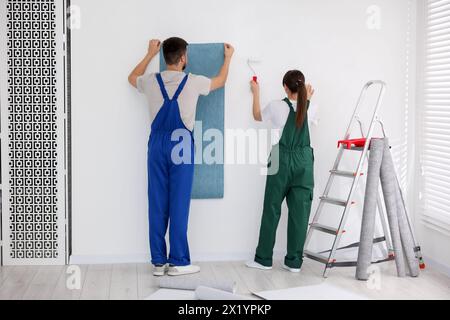 Workers hanging light blue wallpaper in room Stock Photo - Alamy