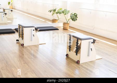 Two modern wooden Pilates reformer machines stand ready in a bright ...