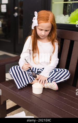 Redhead girl eats ice cream cone Stock Photo - Alamy