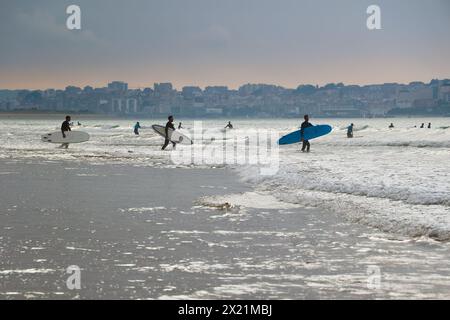View across the bay of Santander with surfers in the shallow surf late ...