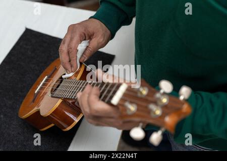 A small four-stringed ukulele with nylon strings lies on old white ...