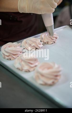 Soft berry zefir mixture is squeezing from pastry bag with starry tip ...