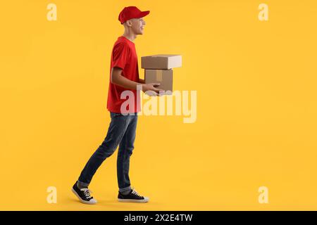 Happy courier with parcels on yellow background. Space for text Stock ...