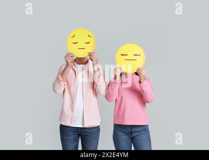 People covering faces with sad emoticons on grey background Stock Photo ...