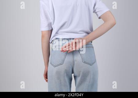 Woman showing open palm behind her back on light background, back view ...