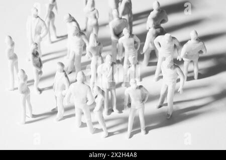 white miniature toy people stand in different poses, men and women on ...