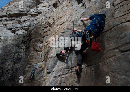 Back of male climber showing foot position and securing rope to quick ...