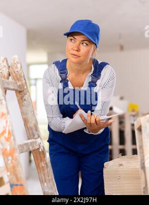 Female designer making checklist while planning building overhaul Stock ...