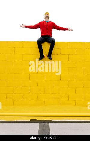 A man in a red hoodie and a white and red baseball cap stands with his ...