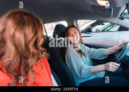 Happy woman driving car with her friend in passenger seat Stock Photo ...